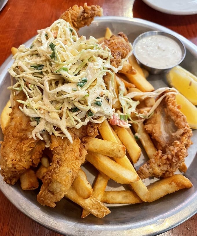 Crispy fish nestled among golden fries and topped with a mountain of slaw—a plate that makes you want to high-five the chef. 