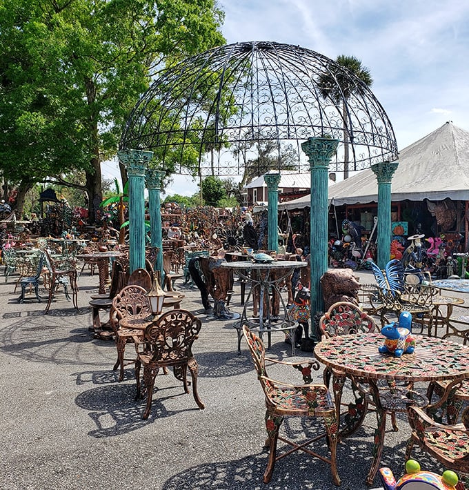 Under a grand metal gazebo, ornate garden furniture creates an outdoor living room where Alice in Wonderland might host a tea party.