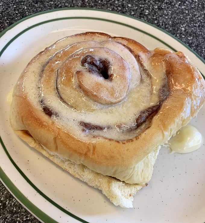 This cinnamon roll isn't just breakfast—it's an event. That glaze isn't merely dripping—it's performing a slow, sweet ballet across warm, pillowy dough that took hours to perfect.