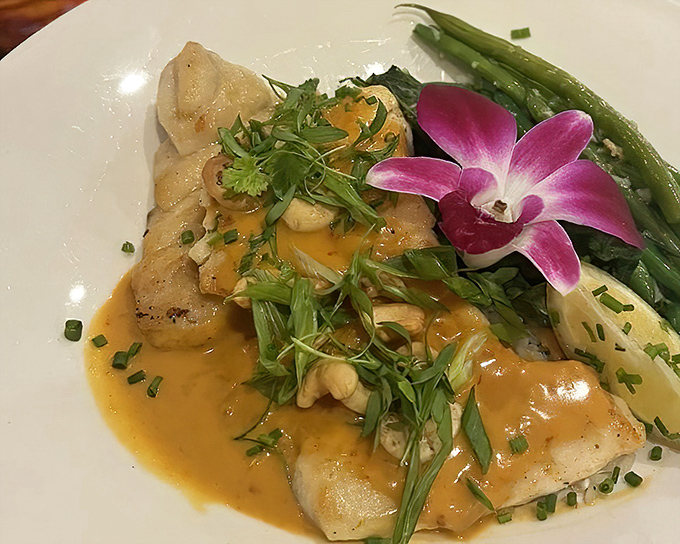 Delicate grouper bathed in a buttery sauce with fresh green beans. The orchid garnish isn't just for show—it's a signature touch.