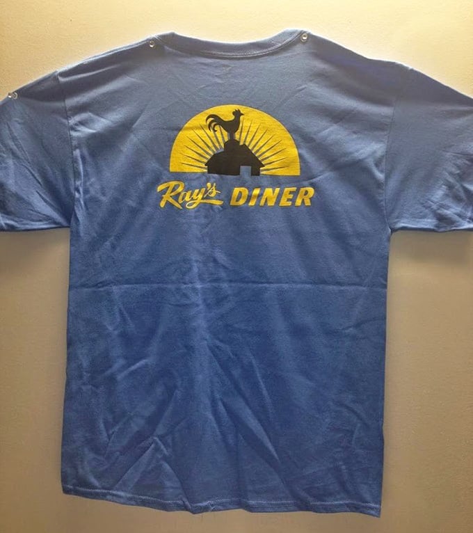 The unofficial uniform of diner devotees. Ray's blue t-shirt with rooster logo—the souvenir that proves you're in the know.