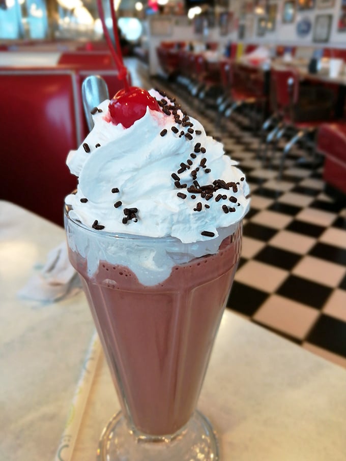 This isn't just a milkshake – it's a towering pink masterpiece topped with whipped cream, sprinkles, and a cherry that would make the Fonz give two thumbs up.