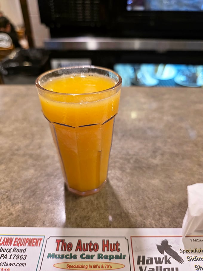 Fresh orange juice in a classic diner glass – nature's perfect beverage against the backdrop of local newspaper ads.