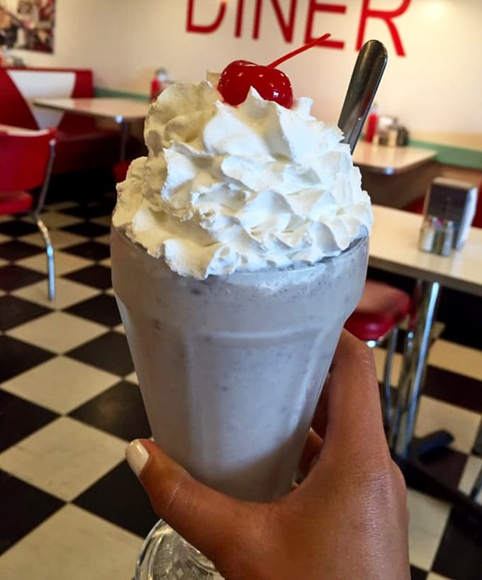 This isn't just a milkshake; it's dessert in a glass – topped with a cloud of whipped cream and that essential cherry exclamation point.