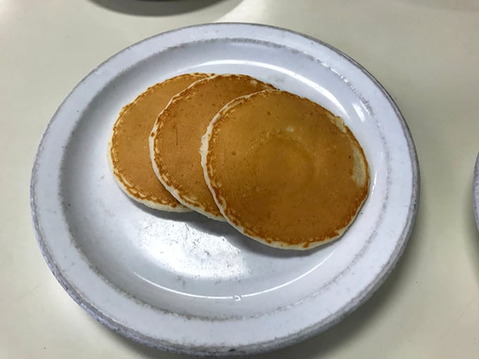Three perfect pancakes await their maple destiny—golden discs of comfort that somehow taste like childhood memories regardless of where you grew up.