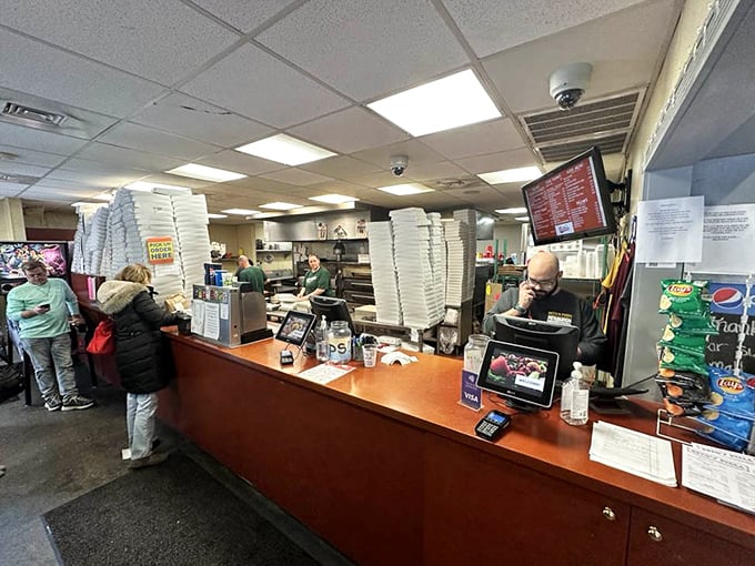 Where pizza dreams become reality—the counter where orders are placed and anticipation begins. Those stacked pizza boxes stand ready for their moment of glory.