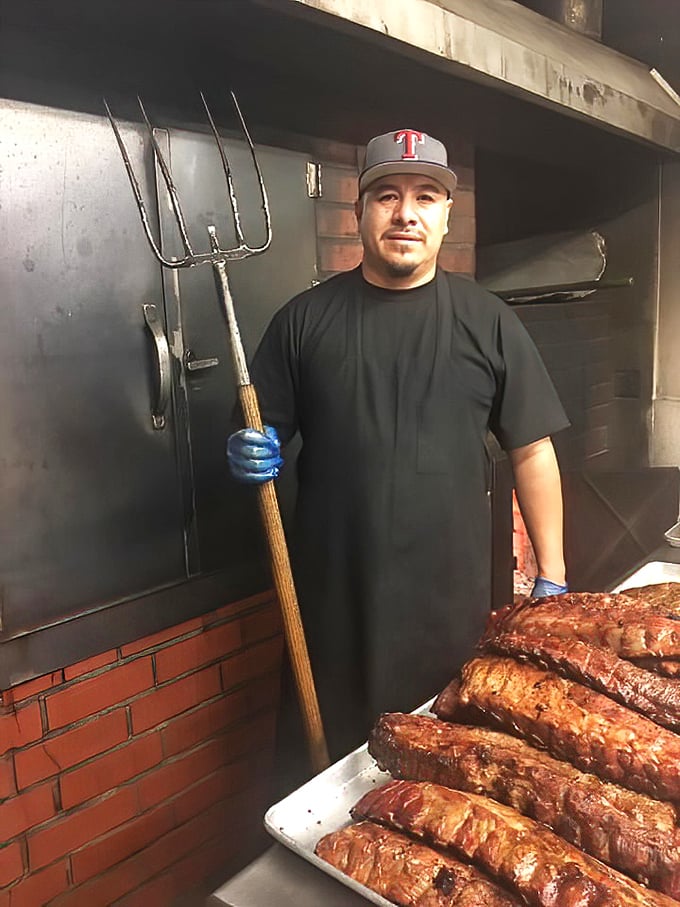 The pitmaster's trident says it all—this is serious BBQ business. Those meats have met their match in skilled hands.