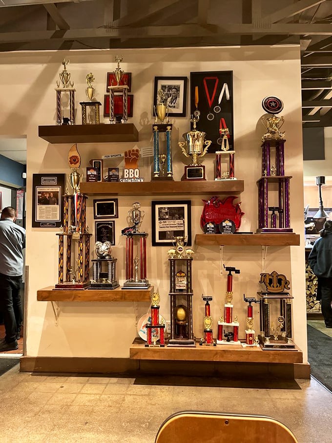 The trophy wall tells the story without words – these folks competed, conquered, and now share their championship barbecue with lucky diners.