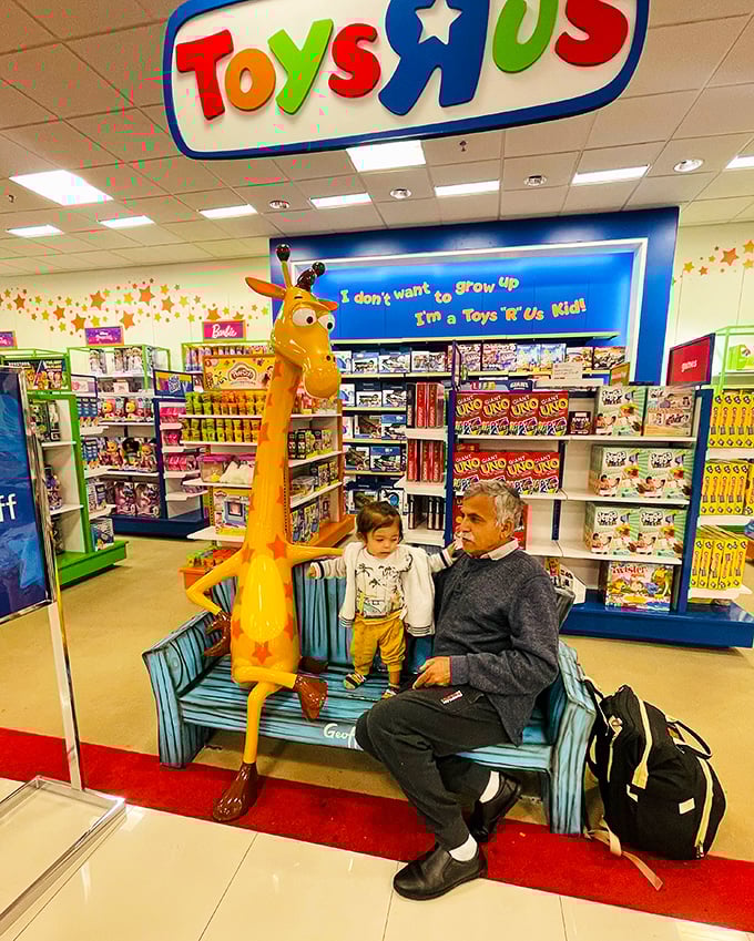 The iconic giraffe bench at Toys"R"Us creates multi-generational moments—where grandparents rest while imaginations run wild through aisles of possibility.