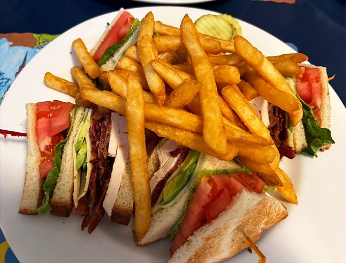 The club sandwich – that three-story architectural marvel that makes you wonder if sandwiches need building permits and structural engineers.