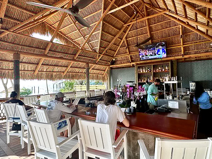 The tiki bar experience done right—palm thatch overhead, ocean breezes all around, and cold drinks flowing as freely as the conversation.