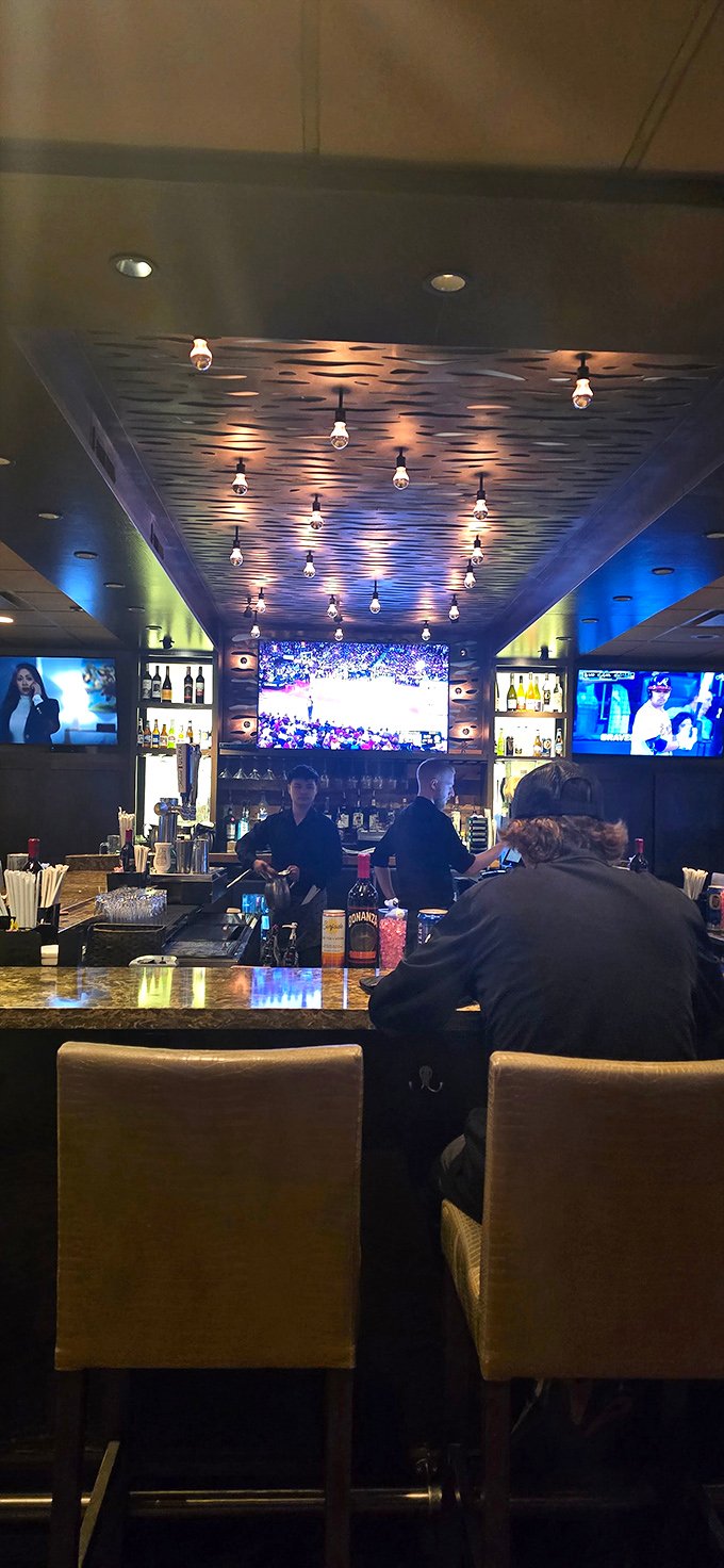 The bar area balances sports-watching practicality with date-night ambiance—Edison bulbs overhead and game-day action on screens create the perfect compromise.