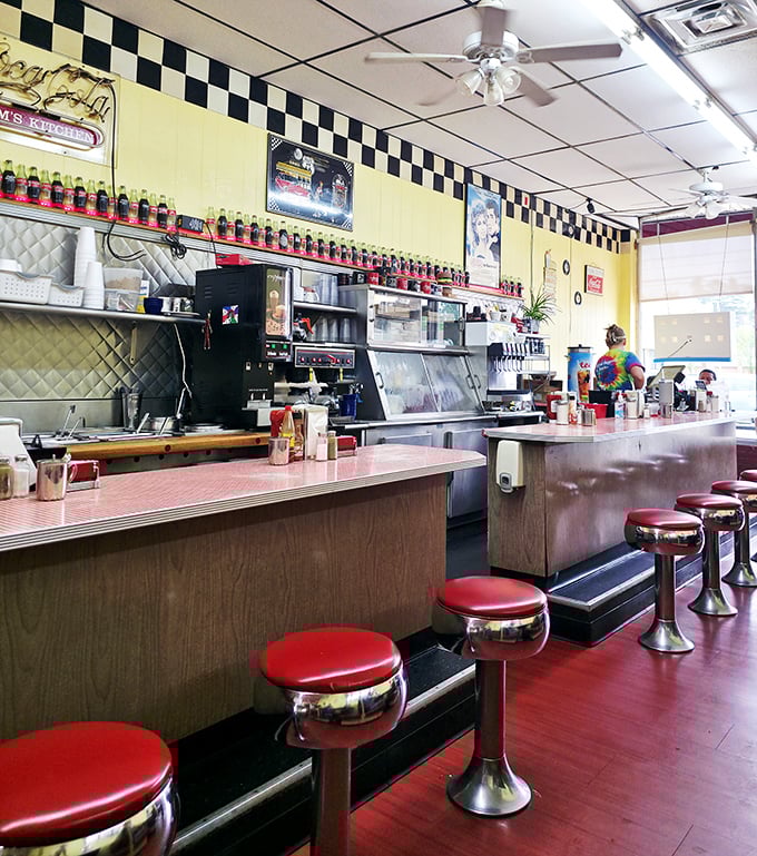The classic diner counter with its row of fire-engine red stools—each one a front-row seat to culinary theater.