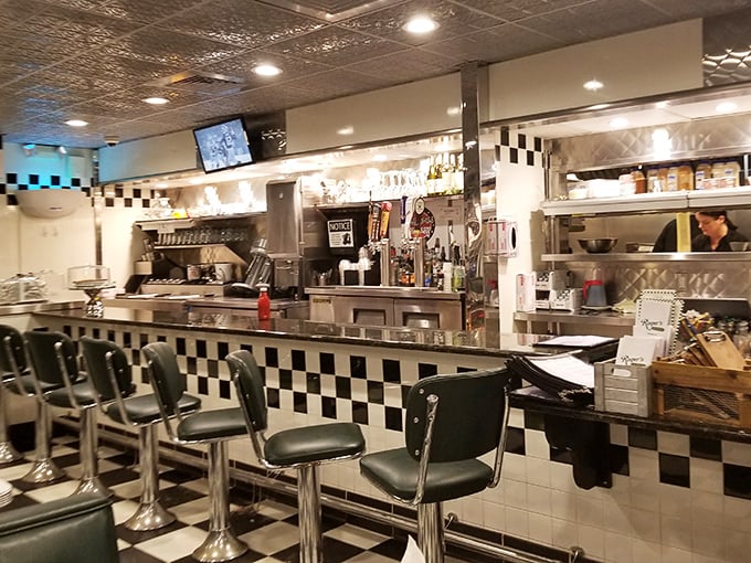 The counter area showcases the heart of diner operations – where orders are called, coffee is poured, and the magic happens behind checkered tiles.