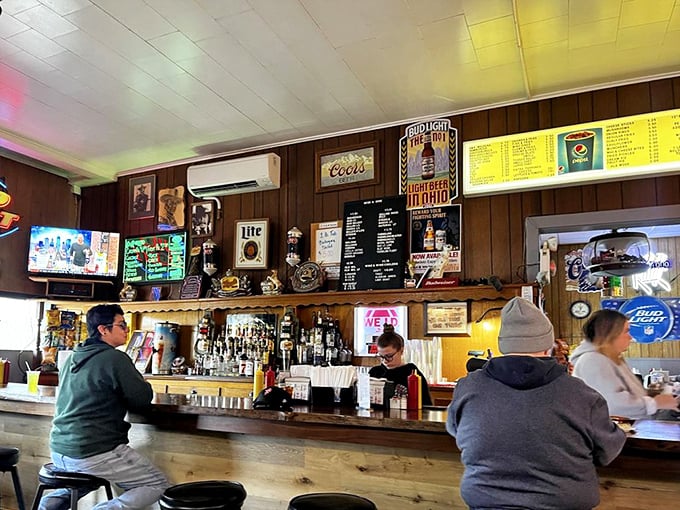 The bar area hums with conversation while beer signs cast their colorful glow across wood-paneled walls that have absorbed decades of laughter.