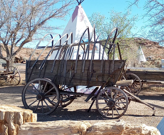 An antique covered wagon sits before the teepees—transportation evolution captured in one perfectly framed Arizona tableau.