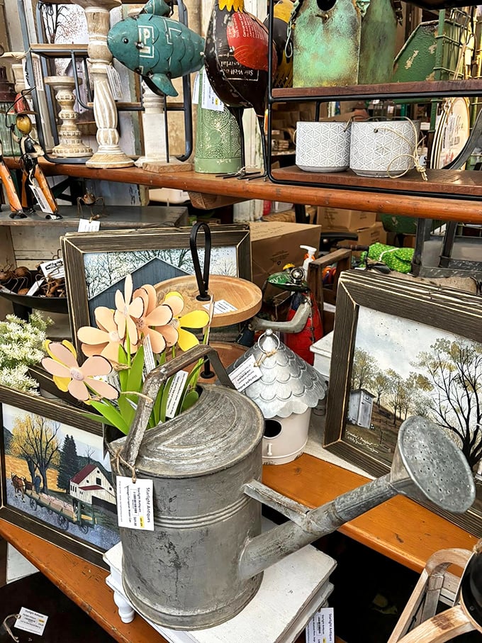 Vintage watering cans and metal flowers mingle with framed rural landscapes, creating garden art that would make your plants feel historically significant.