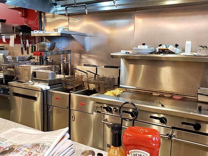 Behind the scenes where breakfast dreams materialize. That flat-top grill has seen more eggs than an Easter bunny convention.