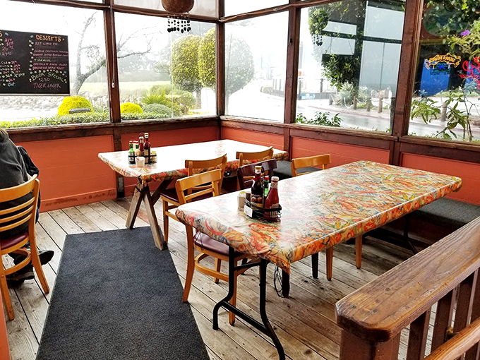 The sunroom dining area offers a greenhouse effect without the humidity—natural light illuminating those colorful tablecloths while you feast.