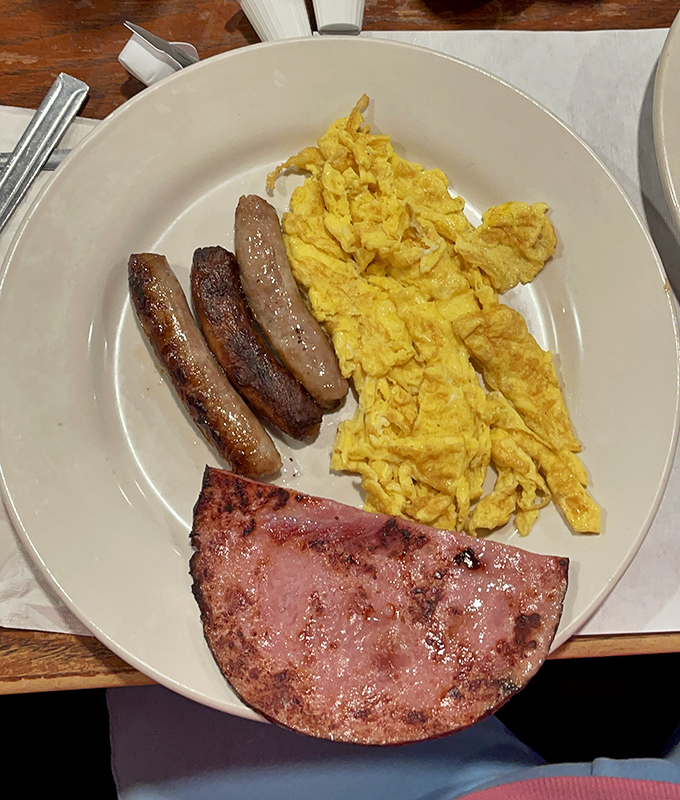 Breakfast simplicity that would make a French chef weep—perfectly cooked sausage, ham, and eggs that prove sometimes less really is more.