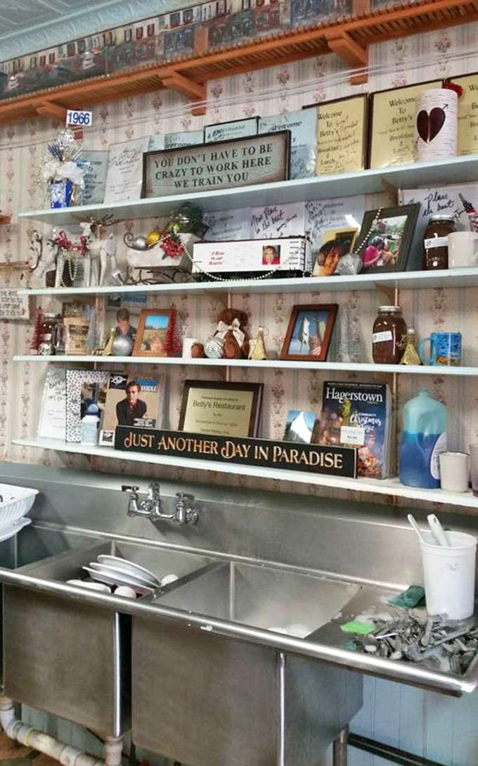 Behind-the-counter shelves packed with trinkets, photos, and that sign reading "Just Another Day in Paradise"—pure diner charm.