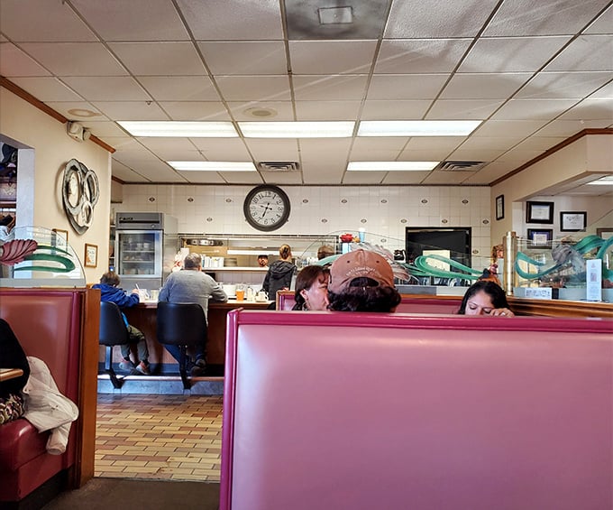 Classic diner geometry: red booths, counter seating, and that magical pass-through window where breakfast dreams materialize into reality.