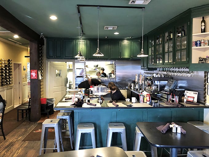 Green cabinets frame the bar area where coffee mugs are filled with the urgency breakfast deserves – caffeine is serious business here.