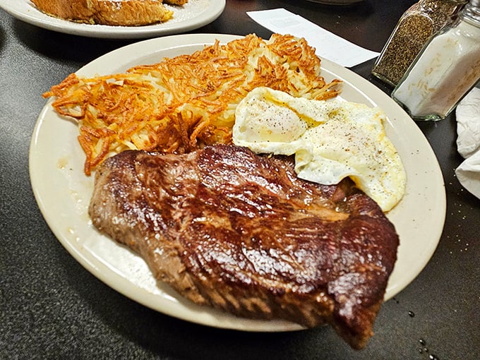 A hearty breakfast plate featuring a perfectly cooked steak, eggs, and those legendary hash browns—the kind of meal that fuels cowboys and office workers alike.