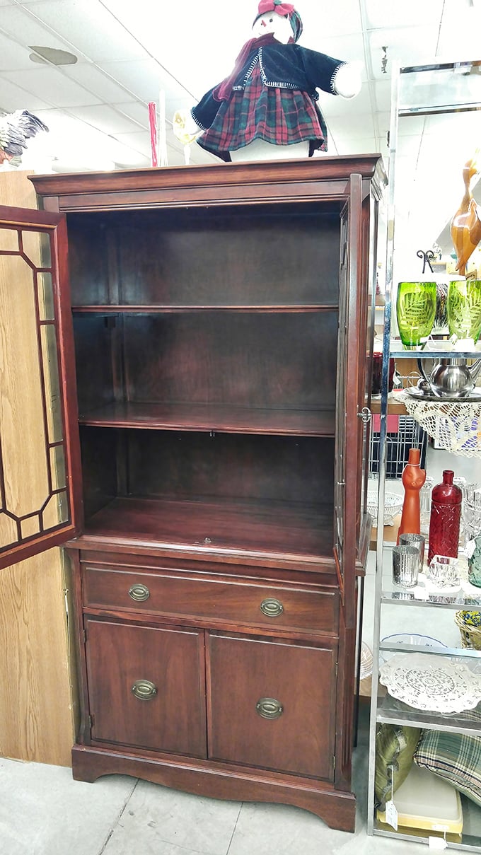 This mahogany cabinet waits patiently for its next home, empty shelves ready to display new treasures. Furniture with more character than most TV personalities.