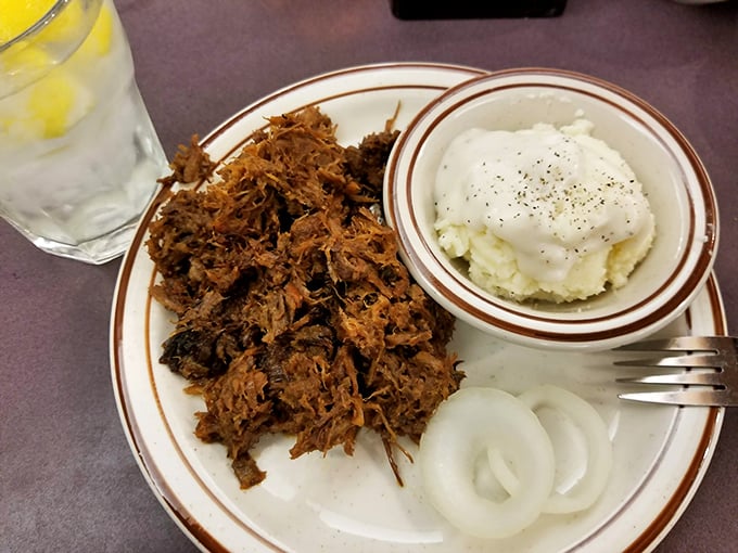 Chopped brisket with that telltale bark, served alongside mashed potatoes and onions—comfort food that speaks fluent Texan.