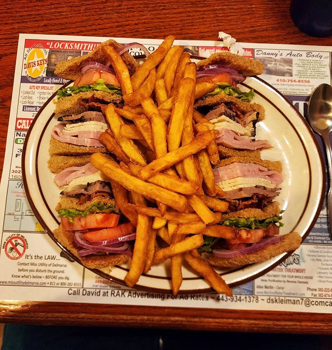 The club sandwich—architecture you can eat. Layers of deliciousness held together by geometry and toothpicks, with fries standing guard.