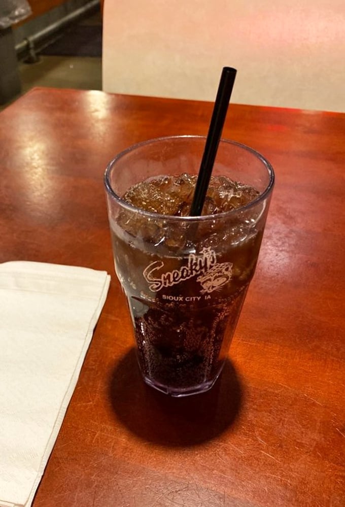 A frosty soda in a Sneaky's branded glass – because every great fried chicken feast deserves its perfect bubbly companion.