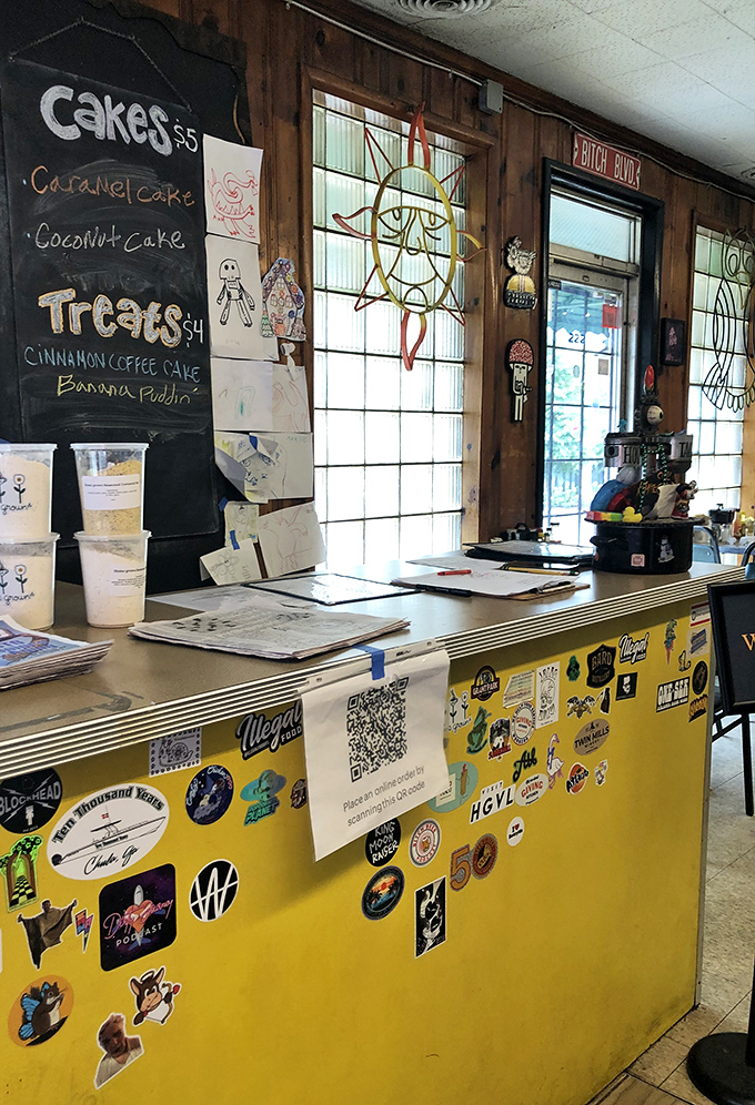 A chalkboard menu of homemade desserts and a counter plastered with stickers—visual proof you're in a place with personality to spare.