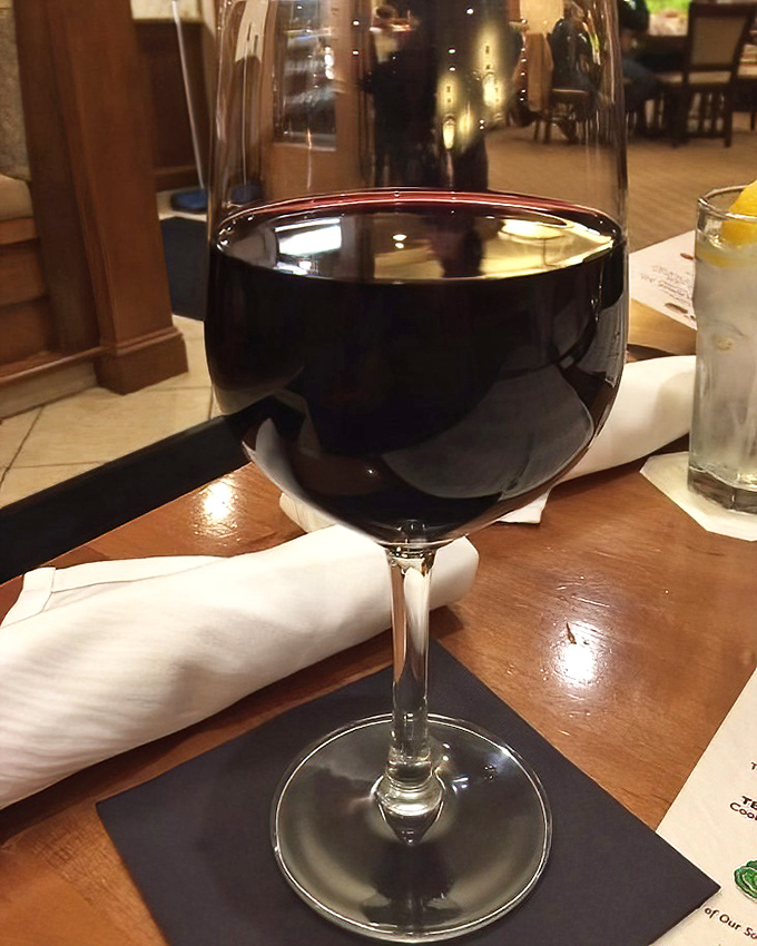 A glass of ruby-red wine catching the light just so—because sometimes a sandwich this good deserves a proper toast.