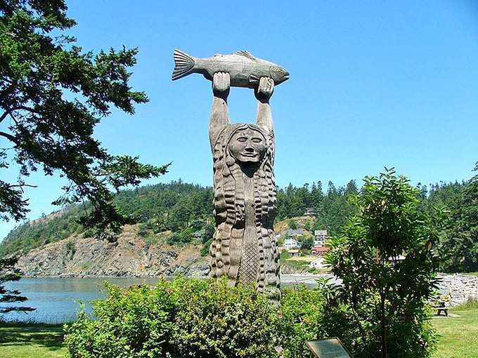 The Maiden of Deception Pass stands sentinel, holding her catch. Native American artistry telling stories in cedar.