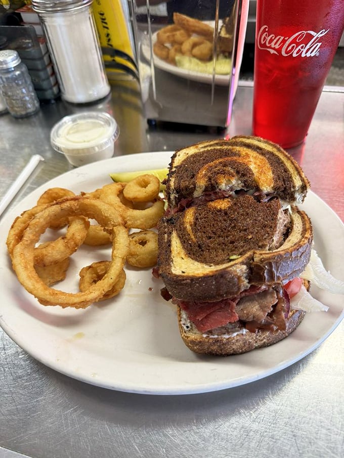 This Reuben sandwich with golden onion rings isn't just lunch – it's an architectural achievement. The marble rye swirl adds both style and substance.