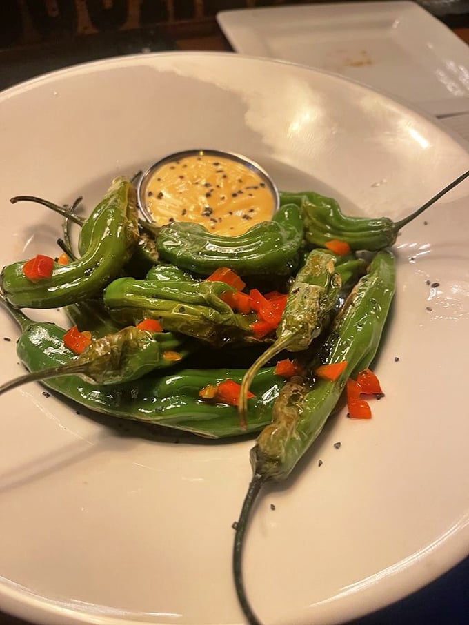 Blistered shishito peppers playing culinary roulette—most are mild, but occasionally one brings the heat. That dipping sauce is liquid gold worth its weight in actual gold.