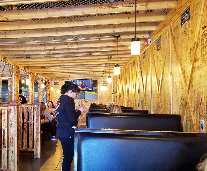 Wooden dividers create cozy dining nooks where seafood feasts unfold and strangers become friends over shared butter sauce techniques.