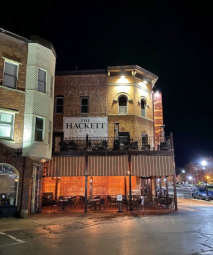 The Hackett Hotel glows with evening promise, its historic façade illuminated like a beacon for those seeking both craft cocktails and local stories.