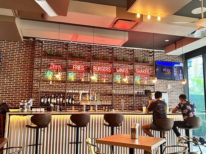 The bar area glows with promise, where neon signs spell out life's essentials: BEER, FRIES, BURGERS, WINGS, SHAKES. Poetry in five words.