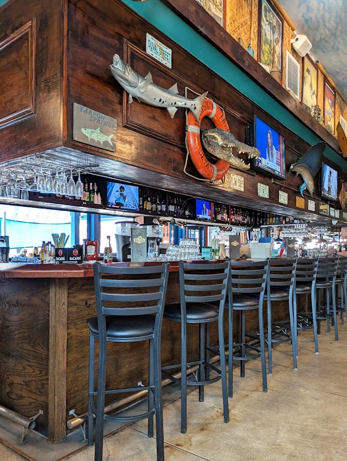 The bar area—where mounted fish keep watch over bottles, and stories flow as freely as the drinks beneath strings of twinkling lights.