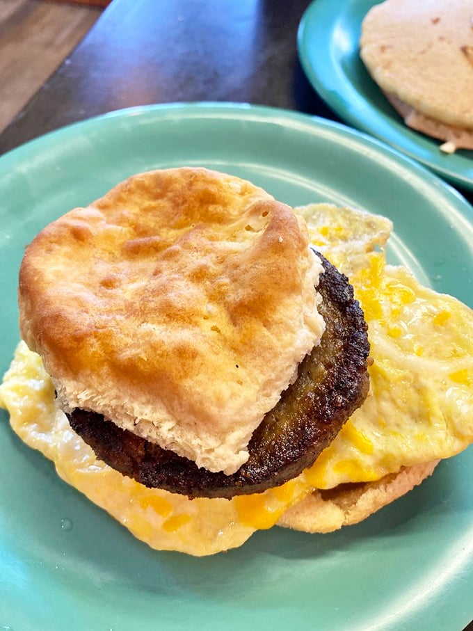 Breakfast sandwich perfection: a golden biscuit embracing sausage and egg with melted cheese that makes morning meetings worth attending.