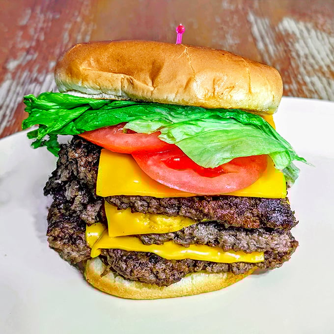 A burger stacked so high it needs architectural support – those layers of beef and cheese create a skyscraper of satisfaction.