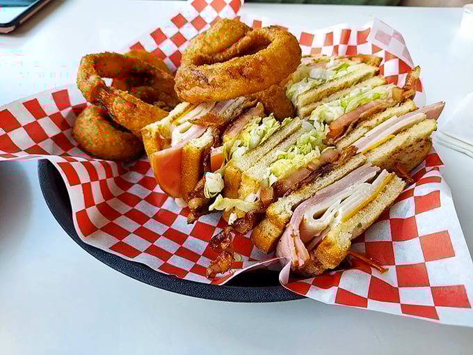 This club sandwich isn't playing around—it's a skyscraper of deli perfection with onion rings as the architectural support beams.