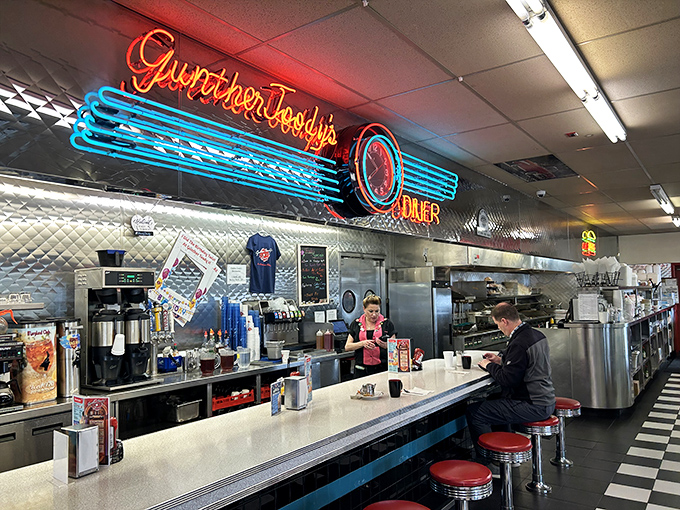 The counter where milkshake magic happens. That neon sign isn't just decoration—it's a beacon guiding hungry travelers to their salvation, one stool at a time.