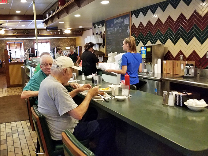 The counter seating—where regulars exchange weather reports and life updates while waitresses perform the ballet of breakfast service.