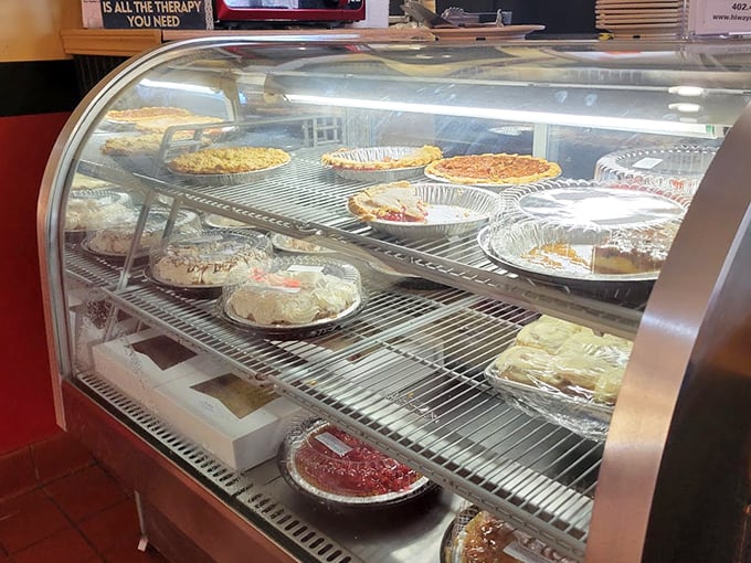 The dessert case – where willpower goes to die. Each pie and cake represents a different way to justify "just one slice."