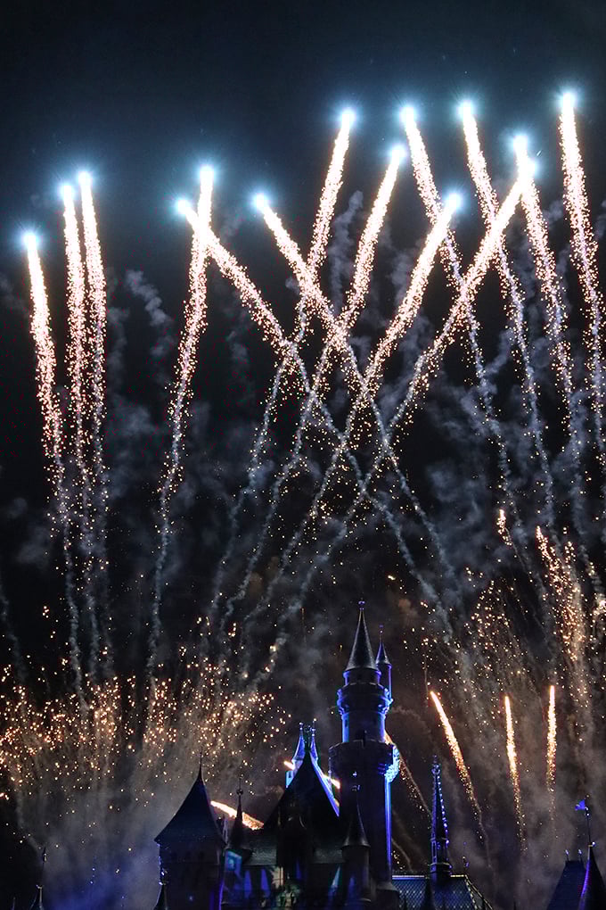 Fireworks explode above illuminated spires, transforming night into a celebration of light that Walt himself would applaud.