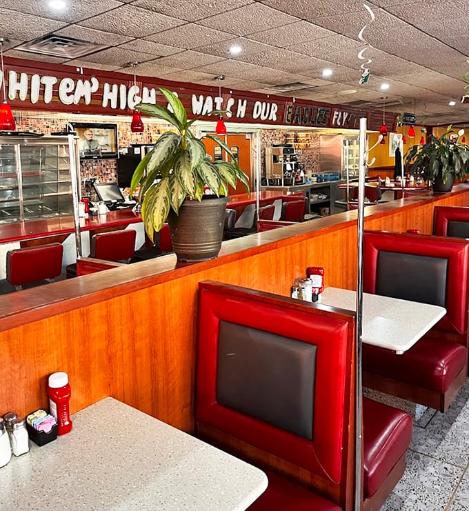 Red booths and wood dividers create the perfect semi-private dining experience. That "Hit 'em High" Eagles sign says you're definitely in Philly.
