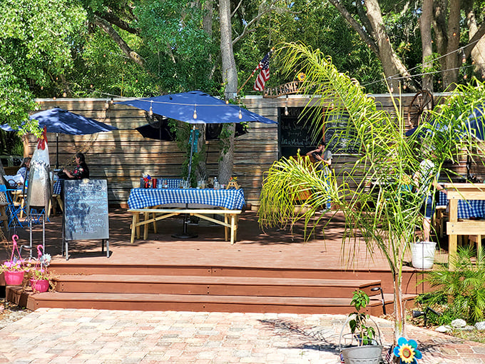 The outdoor seating area offers a taste of Old Florida charm—blue checkered tablecloths under dappled sunlight filtering through native palms.